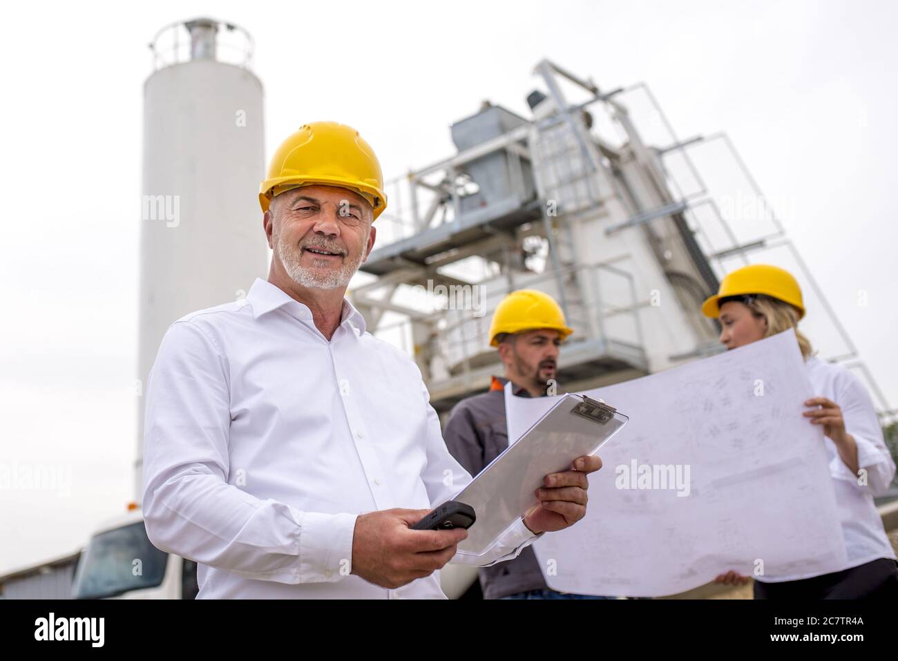 Senior engineer smiling with his colleagues in the background at a ...