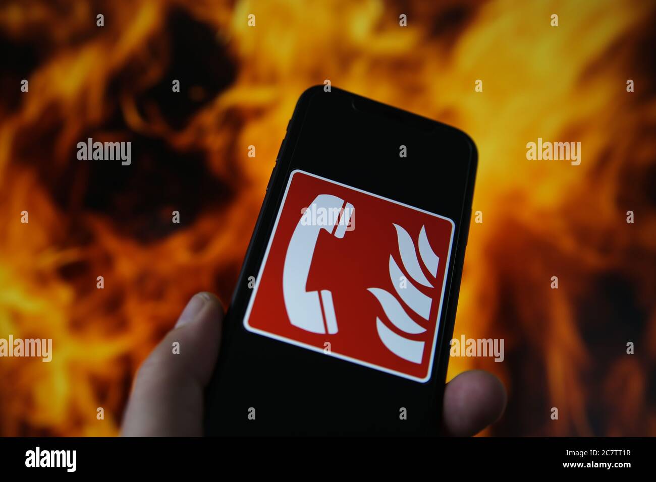 View on hand holding mobile phone with international fire emergency ...