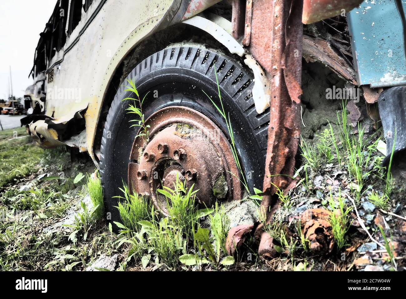 Closeup of a wheel of an old abandoned wrecked bus full of rubbish ...