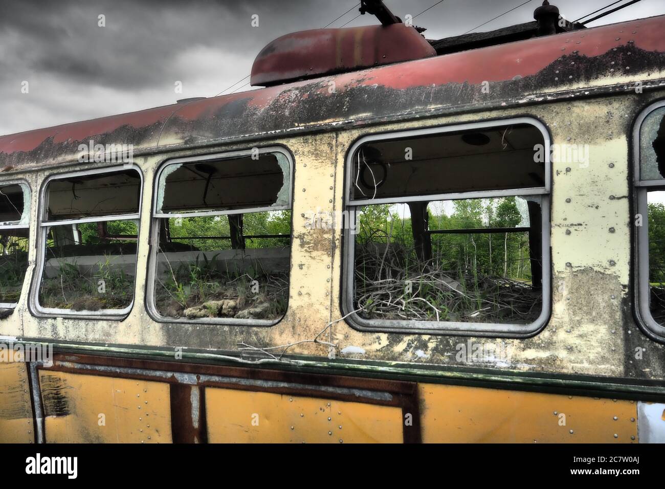 Closeup of an old abandoned wrecked bus full of rubbish and greenery ...