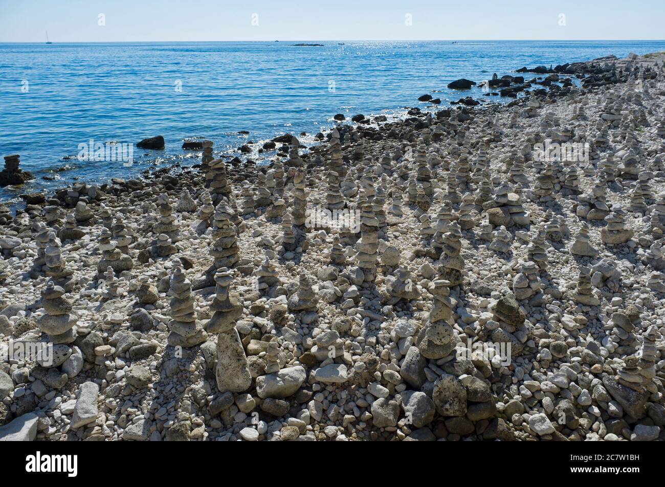 Rovinj beach covered with stacked stones creating one of the most ...