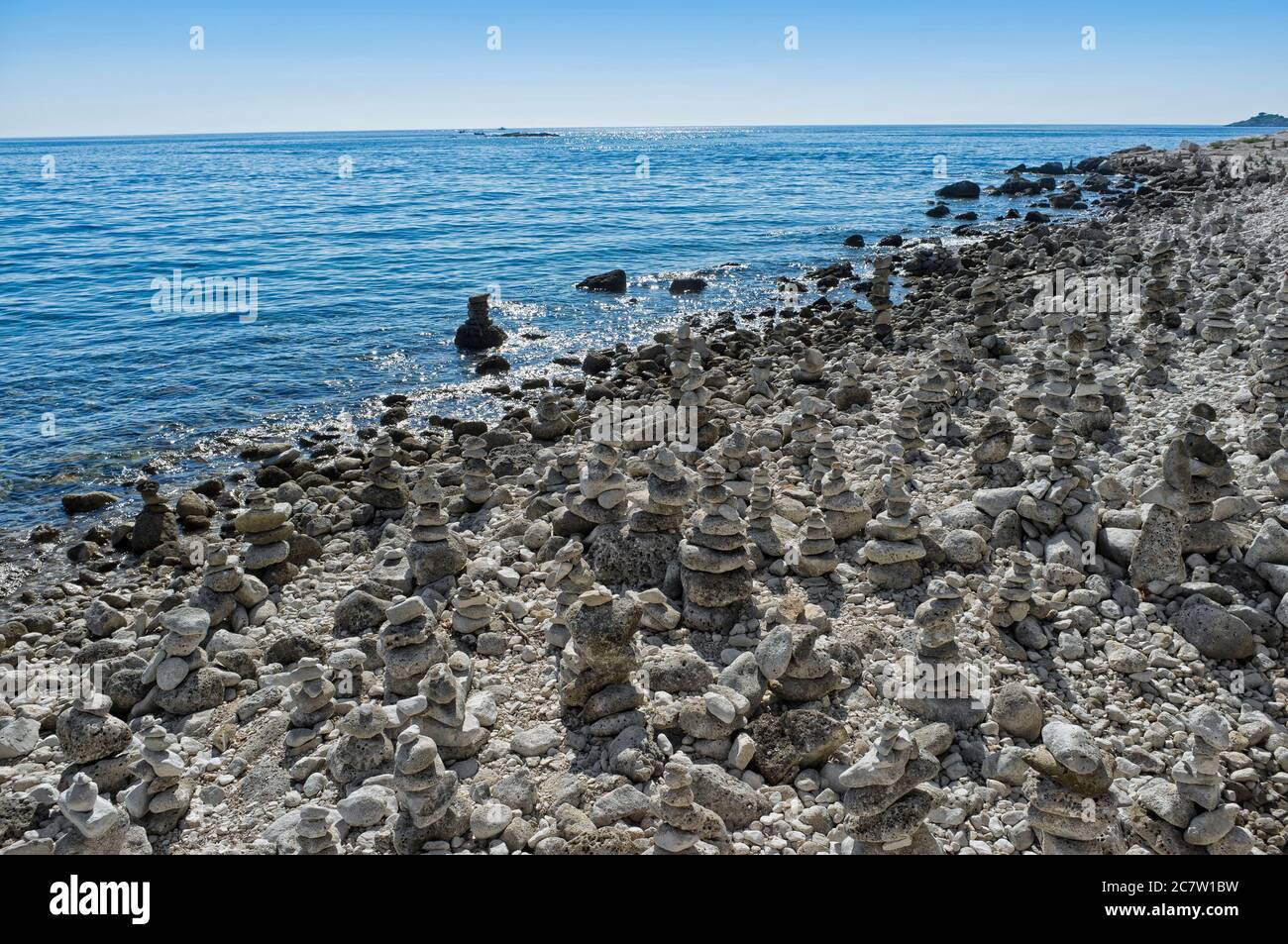 Rovinj beach covered with stacked stones creating one of the most ...