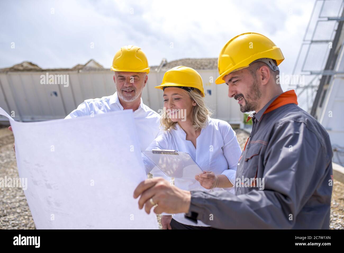 Group of construction workers looking at the plans and documents under ...