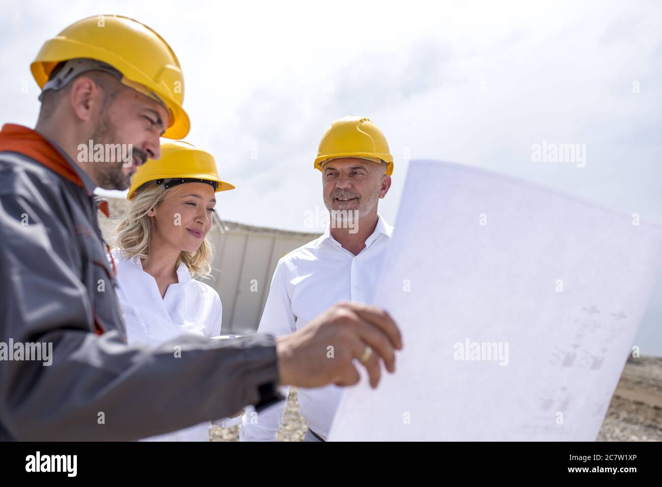 Group of construction workers looking at the plans and documents under ...