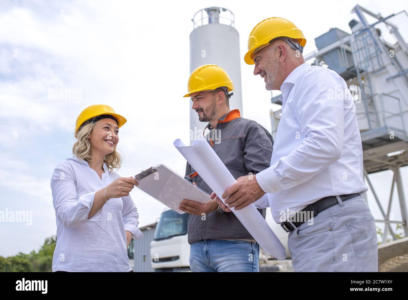 Group of construction workers looking at the plans and documents under ...