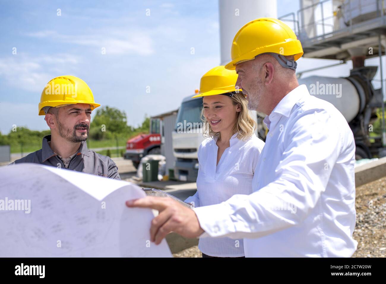Group of construction workers looking at the plans and documents under ...
