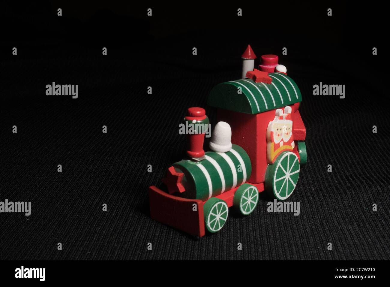 Red children`s Christmas train on a black background. New Year's toy ...