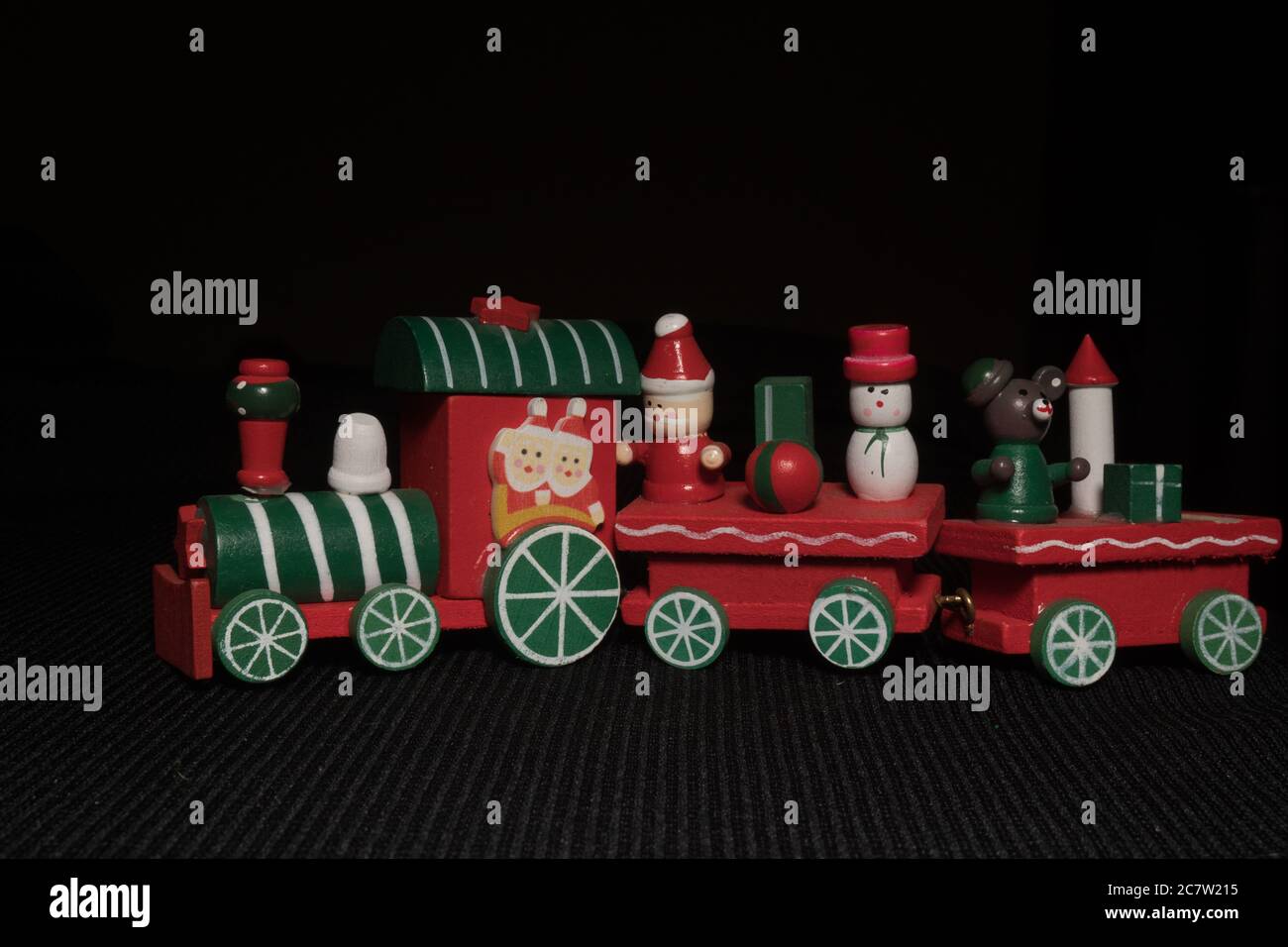 Red children`s Christmas train on a black background. New Year's toy ...