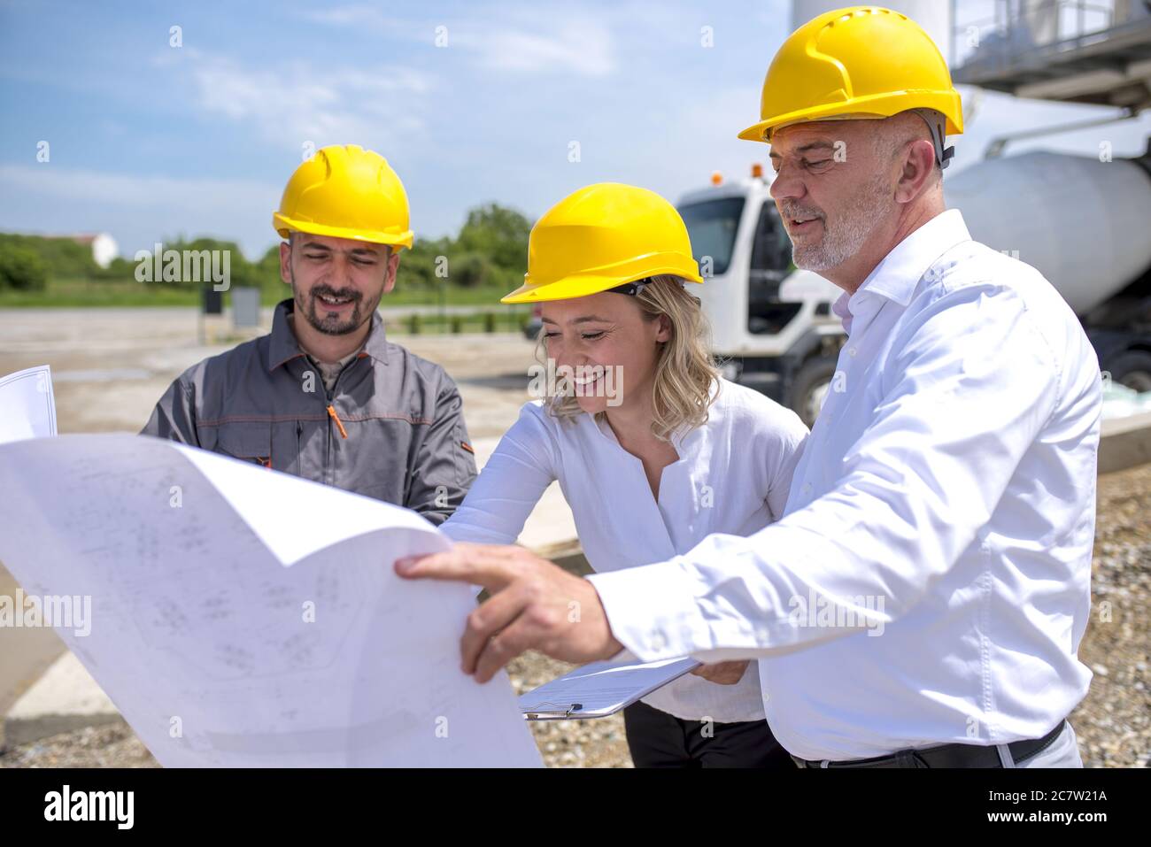 Group of construction workers looking at the plans and documents under ...