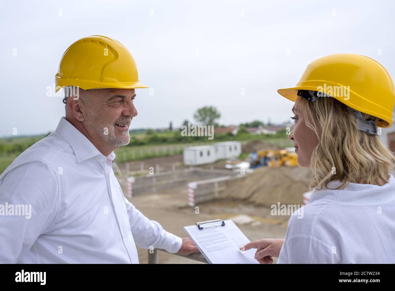 Construction workers with yellow helmets discussing documents under a ...