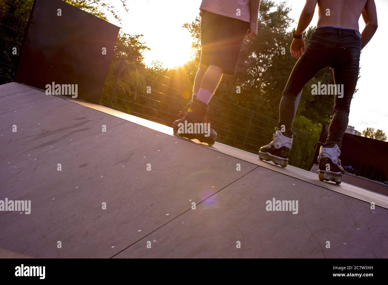Young people rollerblading in a park surrounded by trees under the ...