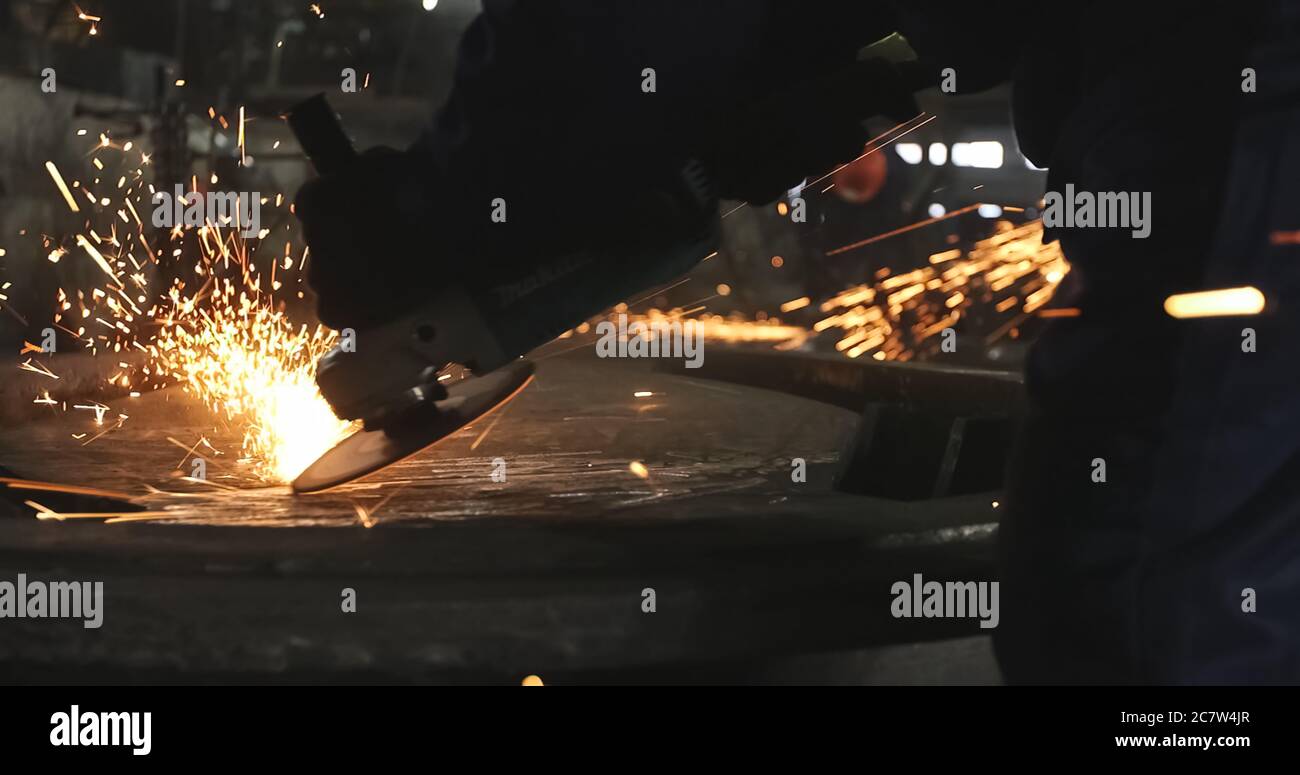 Working in a mask and headphones cleans joints angle grinder on metal ...