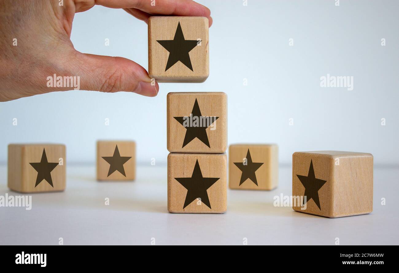 Male hand placing a cube with star icon on top of a other cubes ...