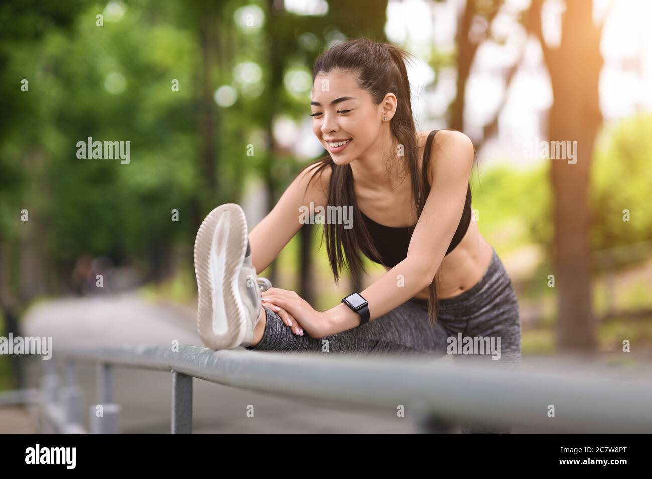 Flexible Asian Girl Stretching Leg Muscles While Working Out In City