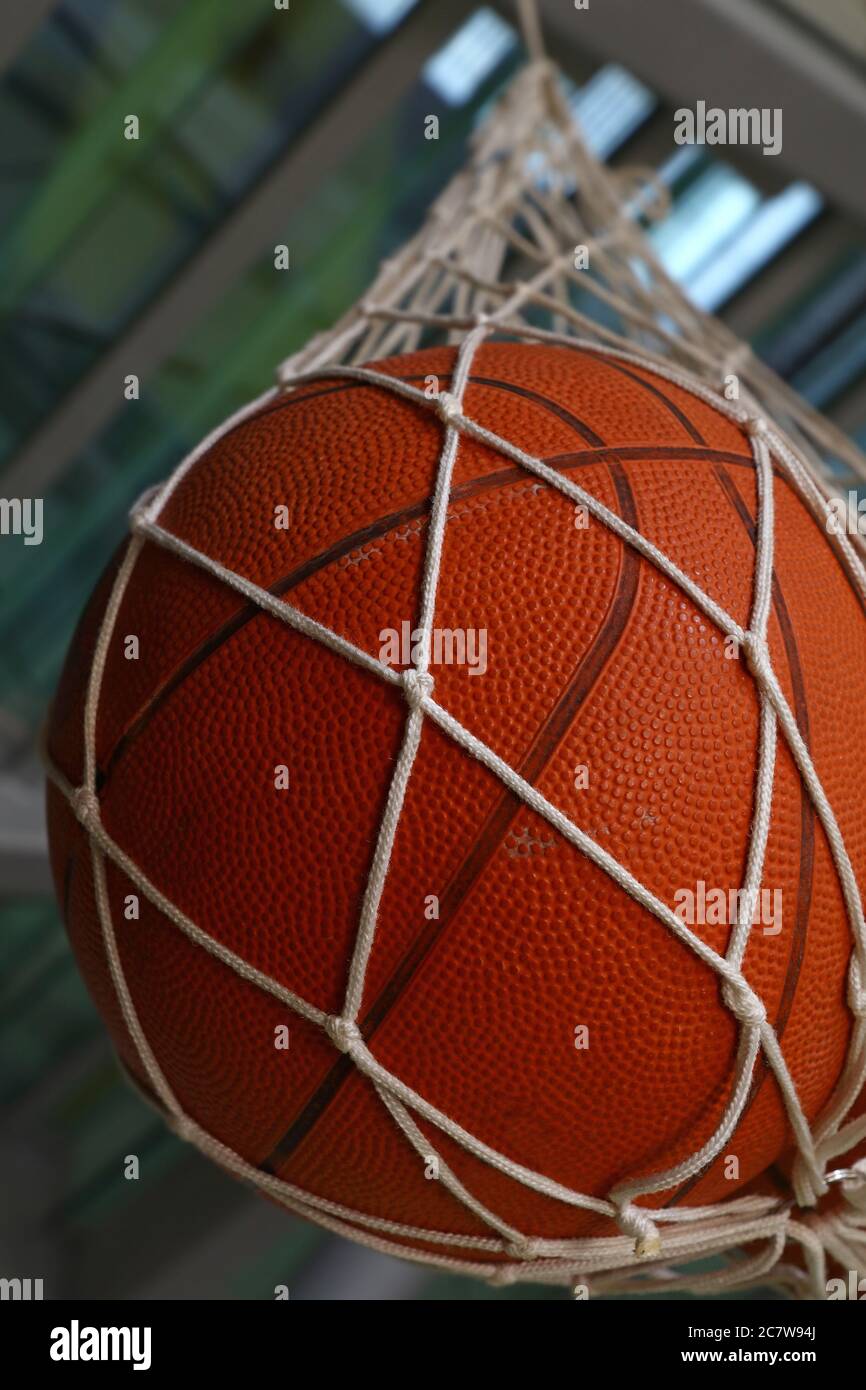 Close up one basketball ball hanging in mesh sack, low angle side view ...