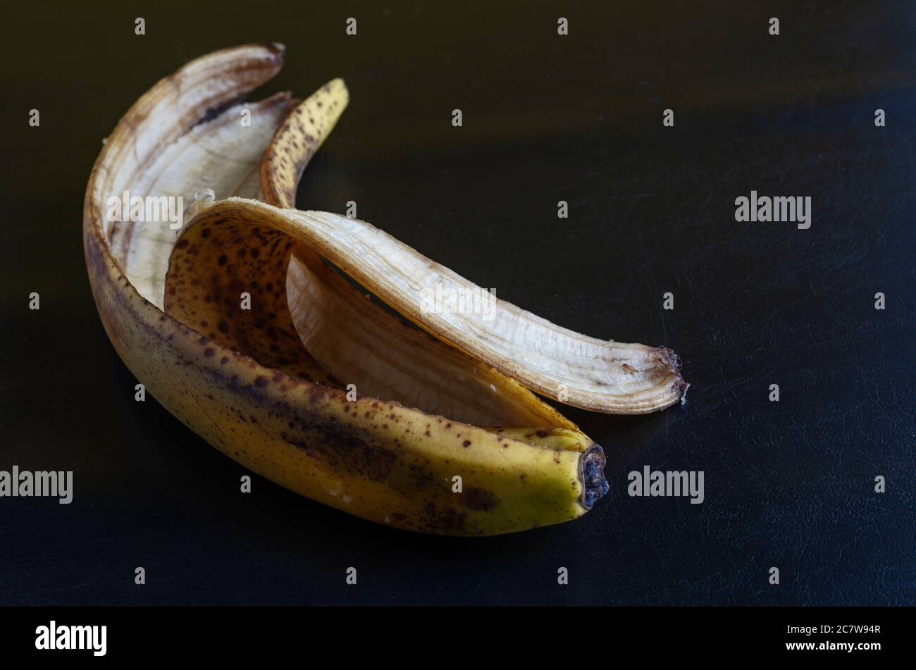Detailed photo Discarded banana peel on black background. Overripe ...