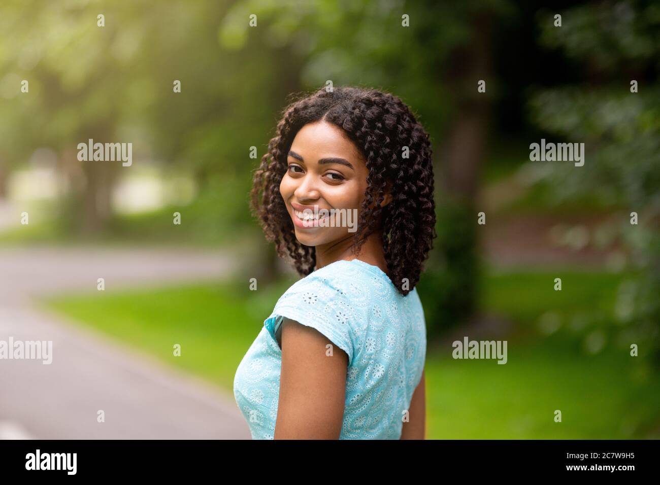 Portrait of pretty African American girl posing at park in summertime ...