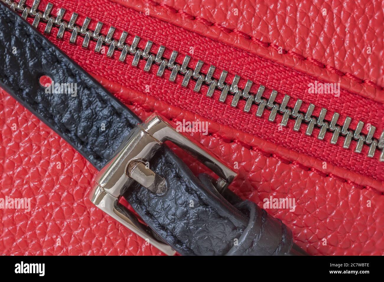 Detail of red leather handbag with zipper and black strap, background ...