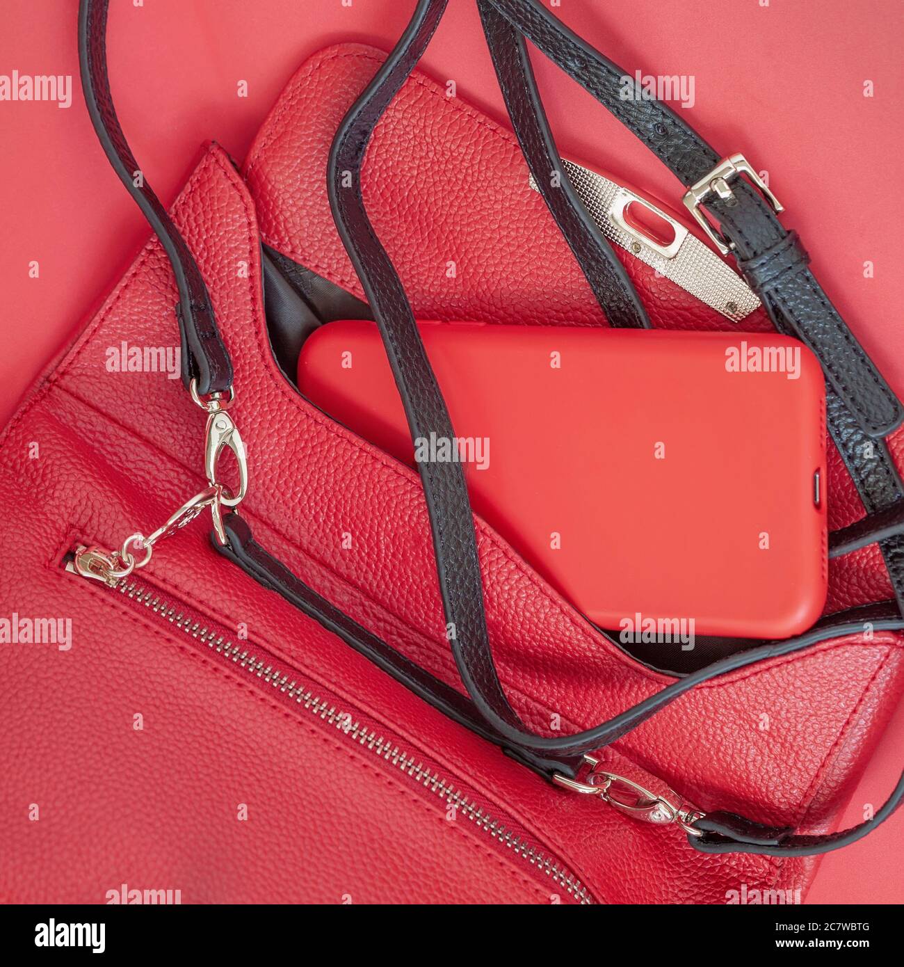 Open small leather handbag with black strap and red mobile phone, top ...