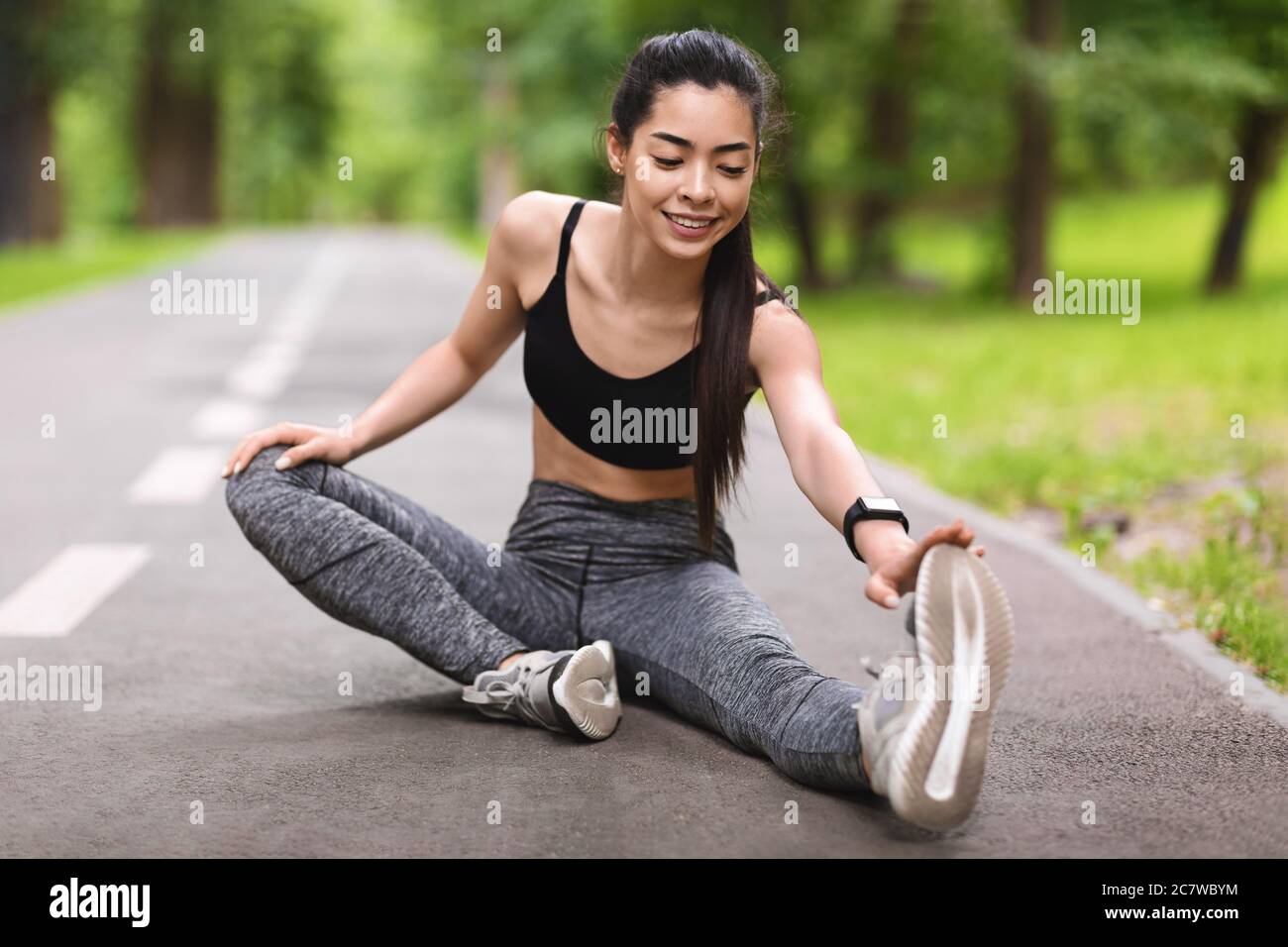 Asian Girl Stretching Leg Muscles After Running In Park, Sitting On ...
