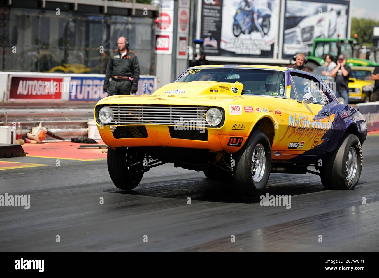 A Chevrolet Camaro rears up on its back wheels accelerating away from ...