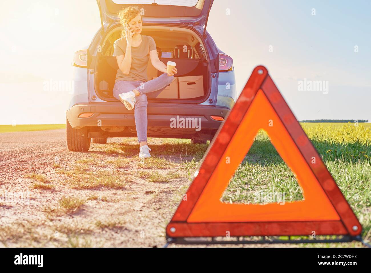 Girl calling for help near car with emergency stop sign. Woman have ...
