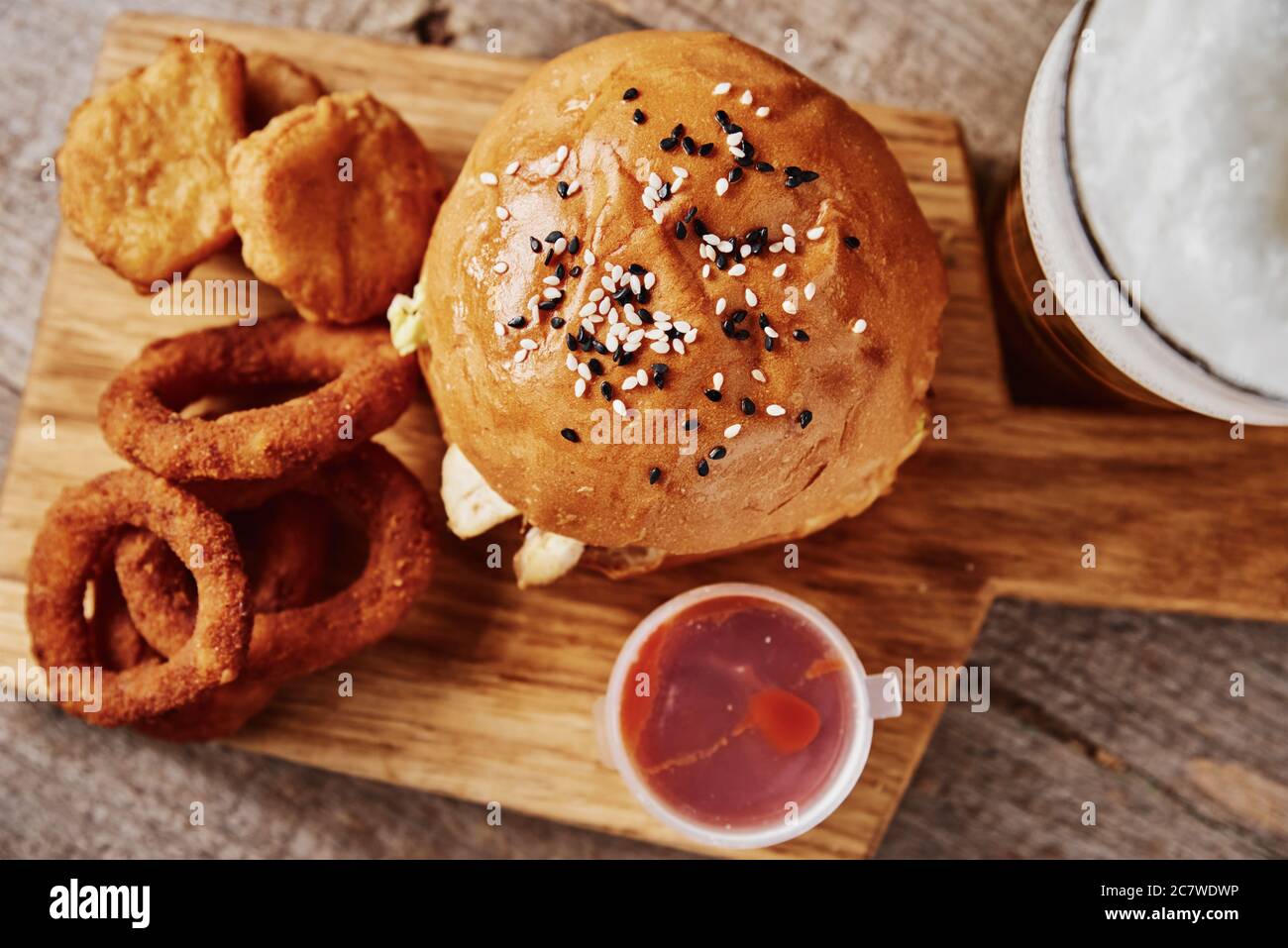Different types of fastfood and snacks and glass of beer on table ...