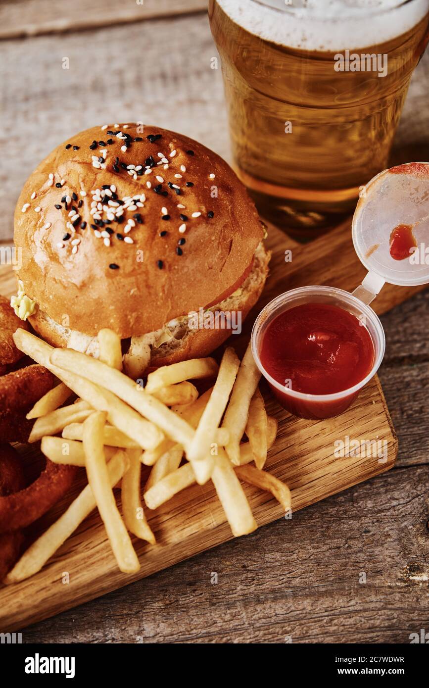 Different types of fastfood and snacks and glass of beer on table ...