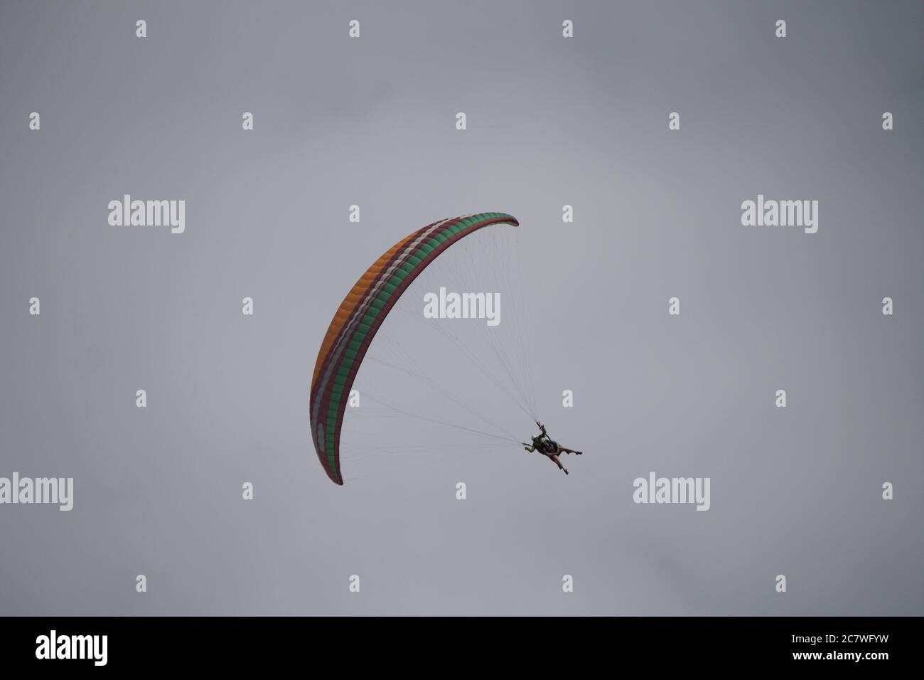 Colorful paraplane flying in the grey shaded sky Stock Photo - Alamy