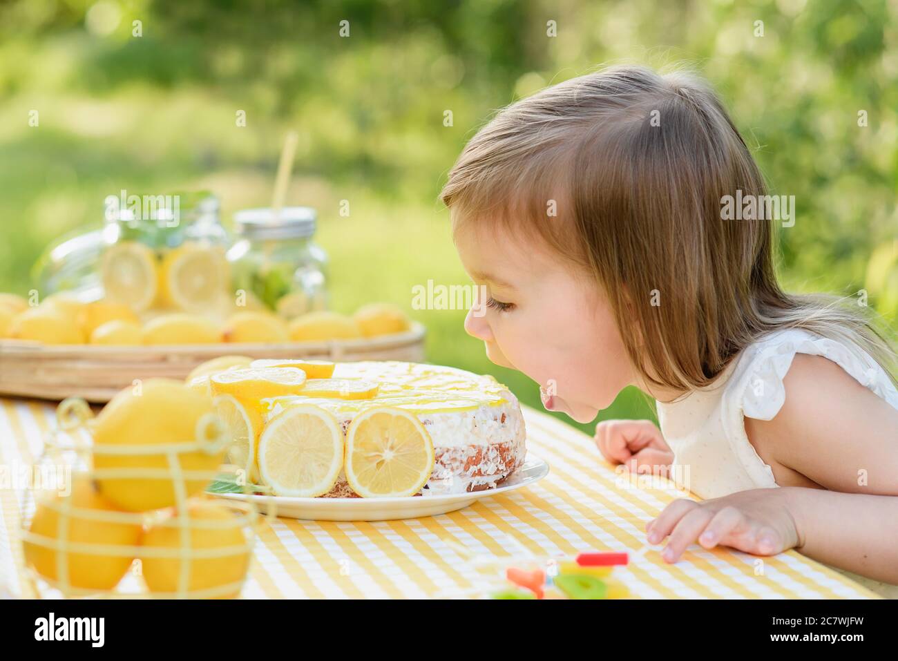 girl eating lemon Birthday cake. Lemonade birthday party at summer park ...