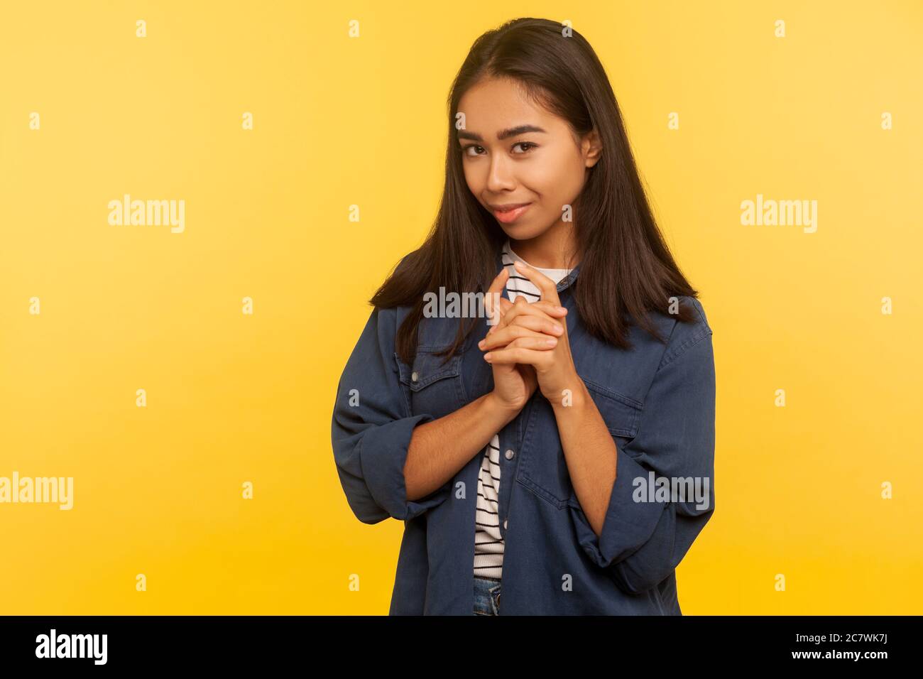 Portrait of sneaky girl in denim shirt smirking and thinking cunning ...