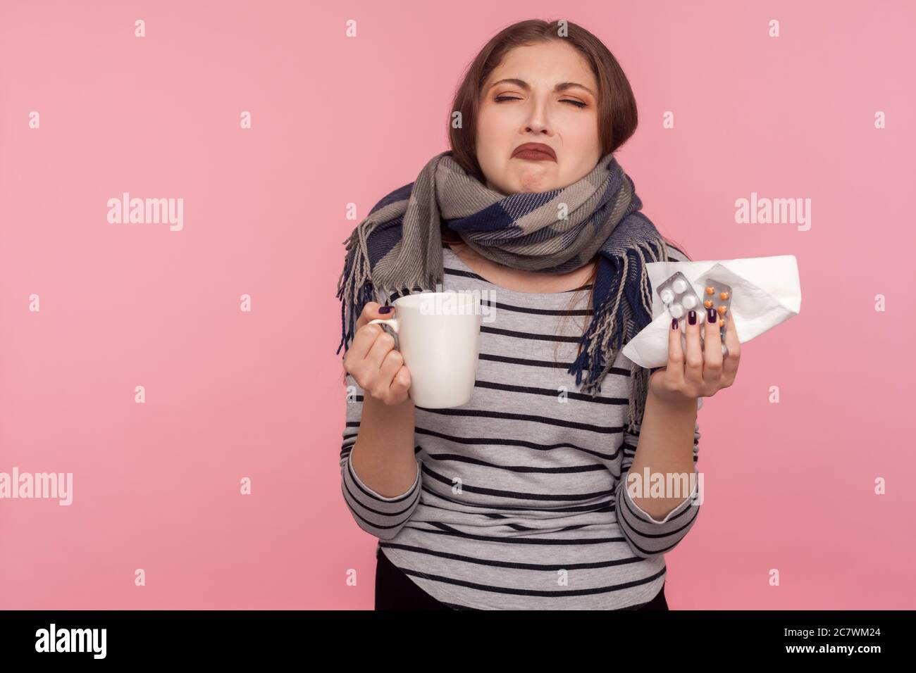 Portrait of ill woman in scarf making miserable face and holding tea ...