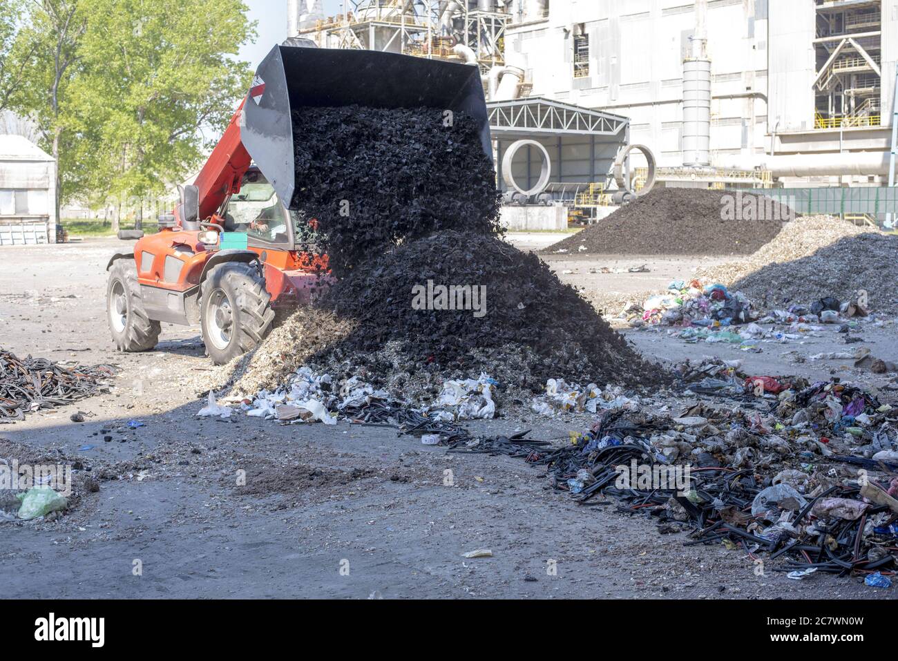 Front loader dumping waste materials at a waste treatment plant Stock ...