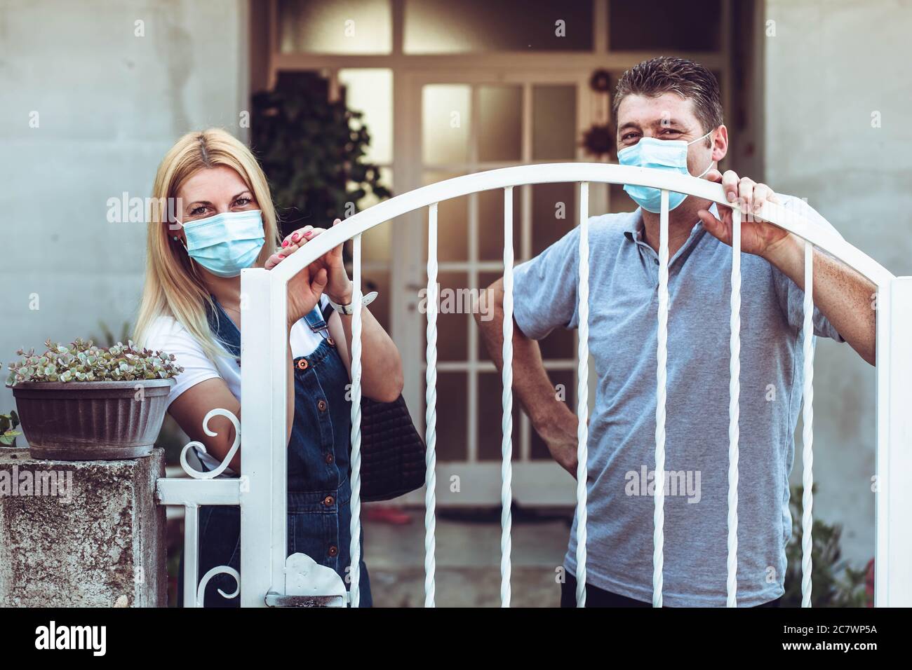Husband and wife at the entrance of their house, wearing a mask ...