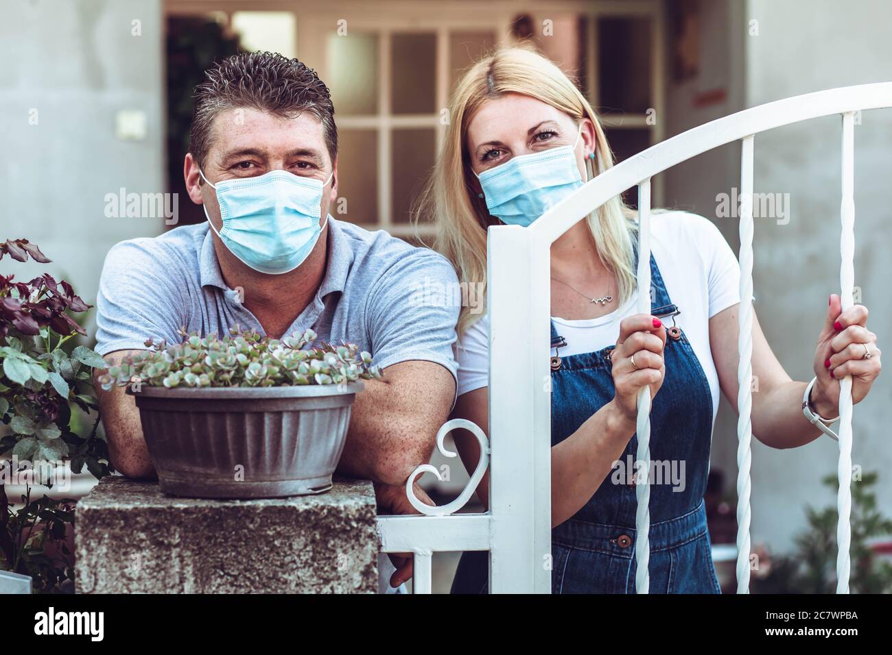 Husband and wife at the entrance of their house, wearing a mask ...