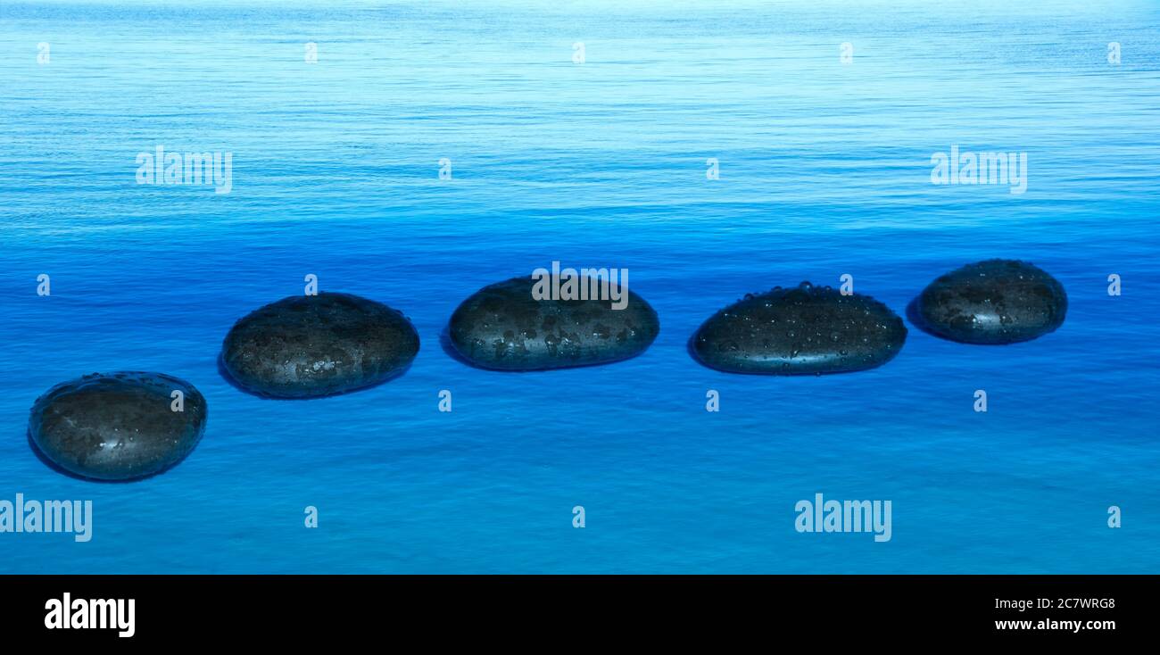 Zen pebbles in blue water Stock Photo - Alamy