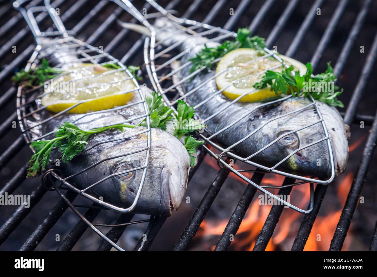 Grilling fresh fish with herbs and lemon on grill Stock Photo - Alamy