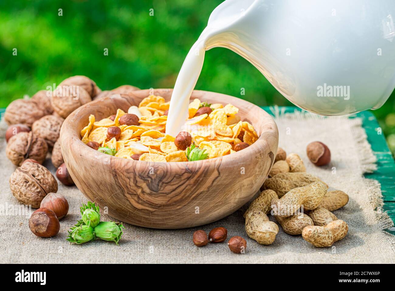 Pouring milk into tasty corn flakes with nuts for breakfast Stock Photo ...