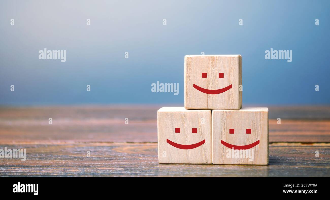 Smiling faces on wooden blocks. Feedback, critic's assessment, service ...