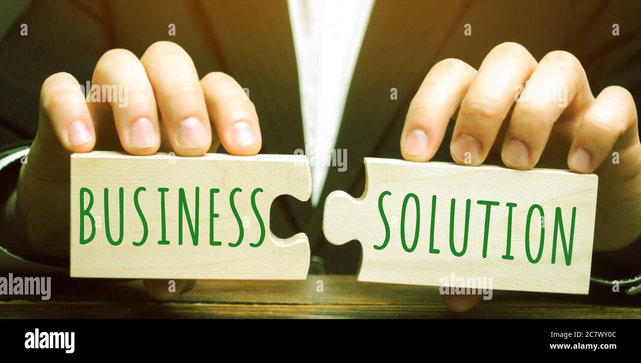 A businessman holds wooden puzzles with the words Business Solution ...