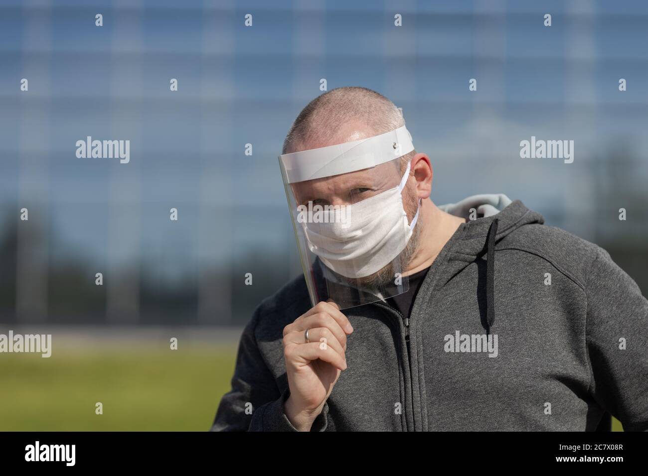 Adult man posing in a protective transparent visor and a white mask on ...
