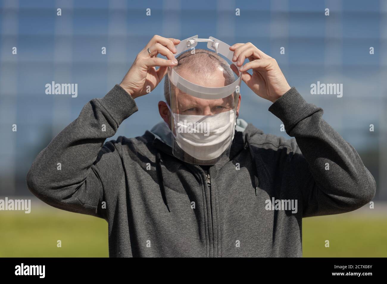 Adult man posing in a protective transparent visor and a white mask on ...