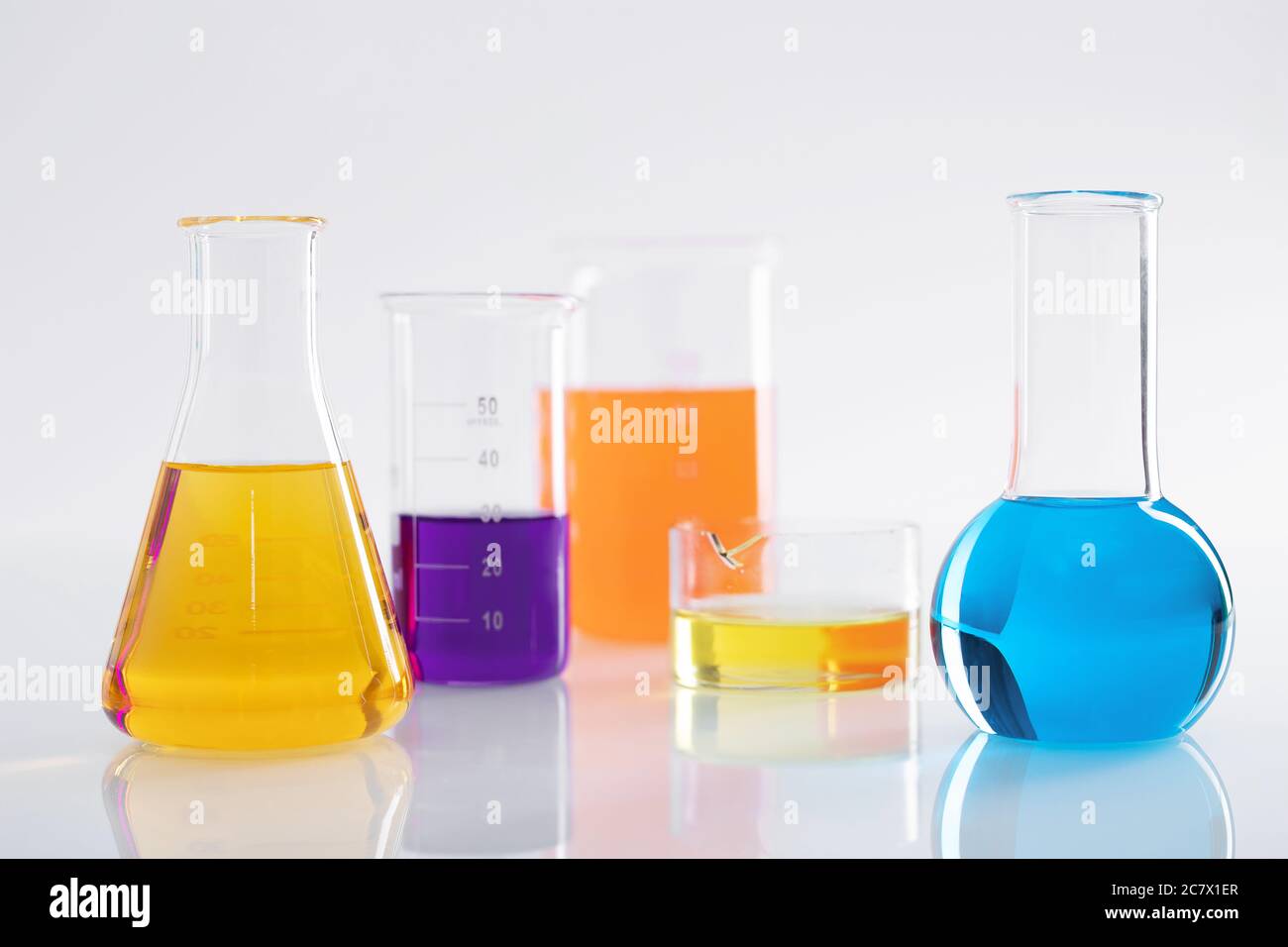 Group of different flasks with colorful liquids on a white background ...