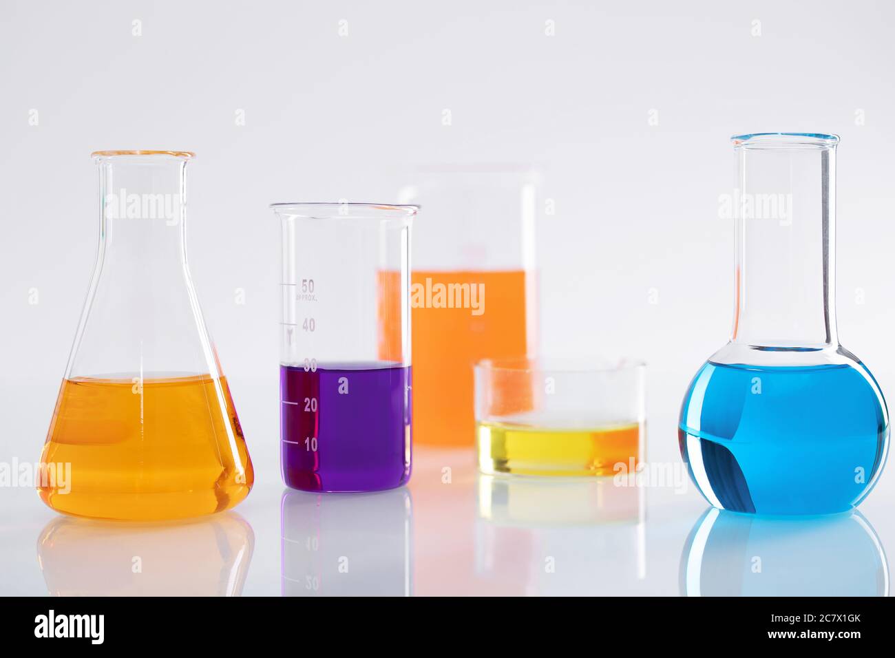 Group of different flasks with colorful liquids on a white background ...