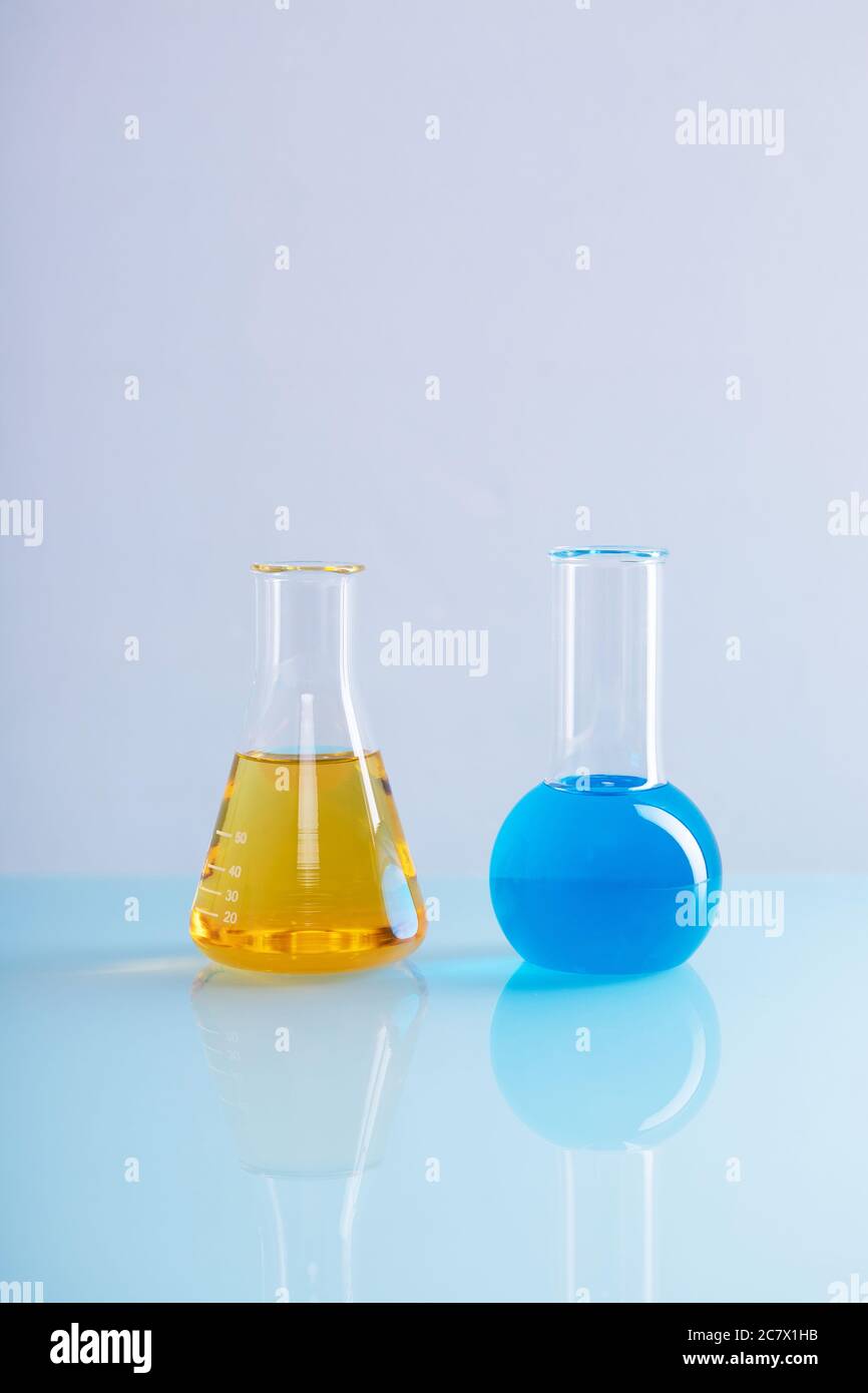 Vertical shot of Erlenmeyer flask with yellow liquid and a round flask ...