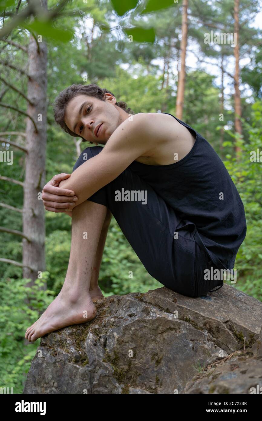 Side view portrait of thoughtful man hugging knees while sitting on ...