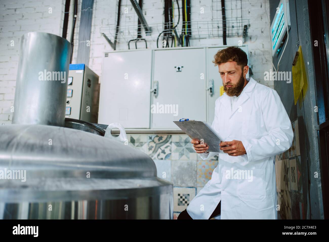 Caucasian male technologist expert in white suit operating production ...