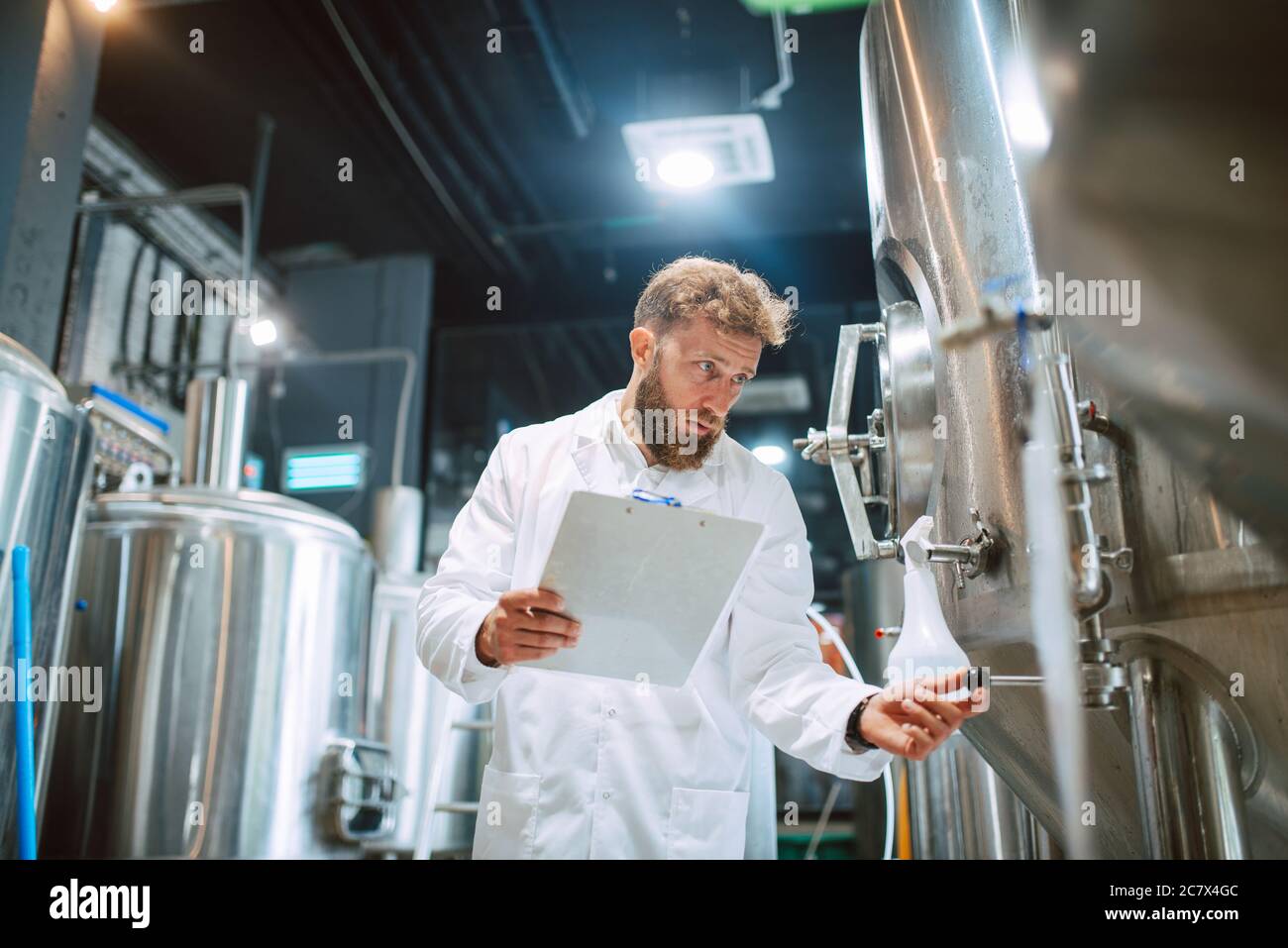 Caucasian male technologist expert in white suit operating production ...