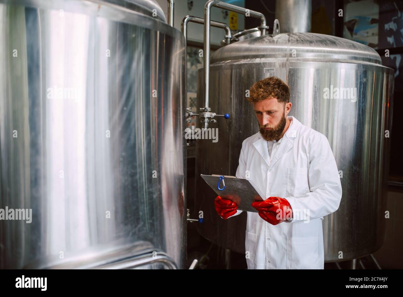 Caucasian male technologist expert in white suit operating production ...