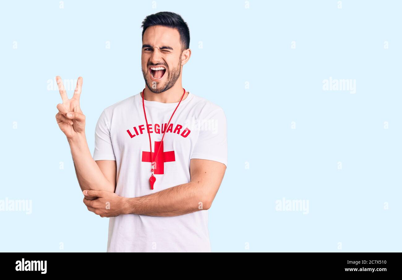 Young handsome man wearing lifeguard uniform smiling with happy face ...